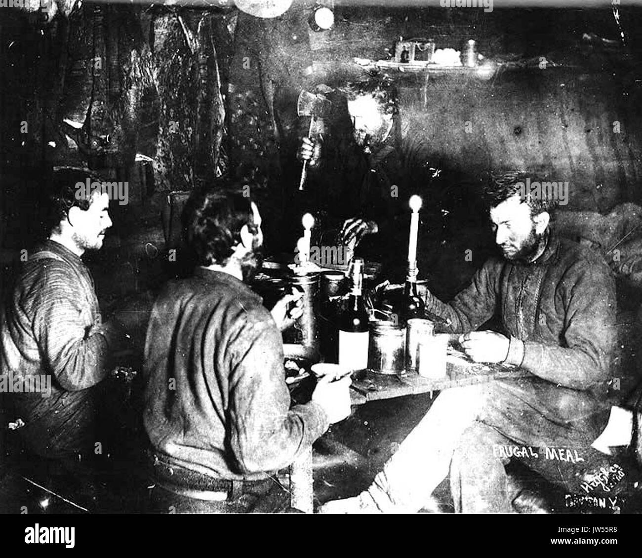 Four miners in a cabin eating dinner by candlelight, probably Yukon ...
