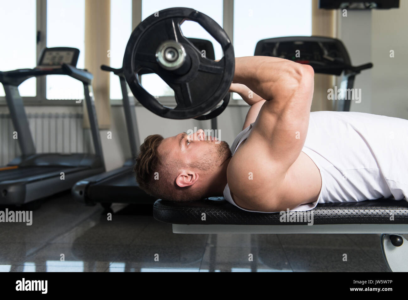 Muscular Man Doing Heavy Weight Exercise For Triceps With Barbell In ...