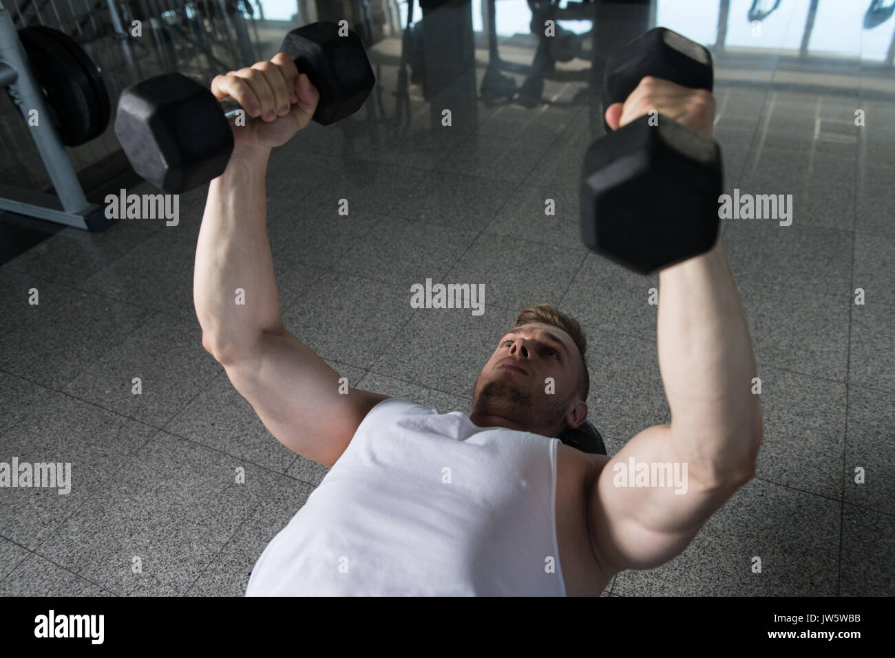Muscular Young Man Doing Heavy Weight Exercise For Chest With Dumbbells ...