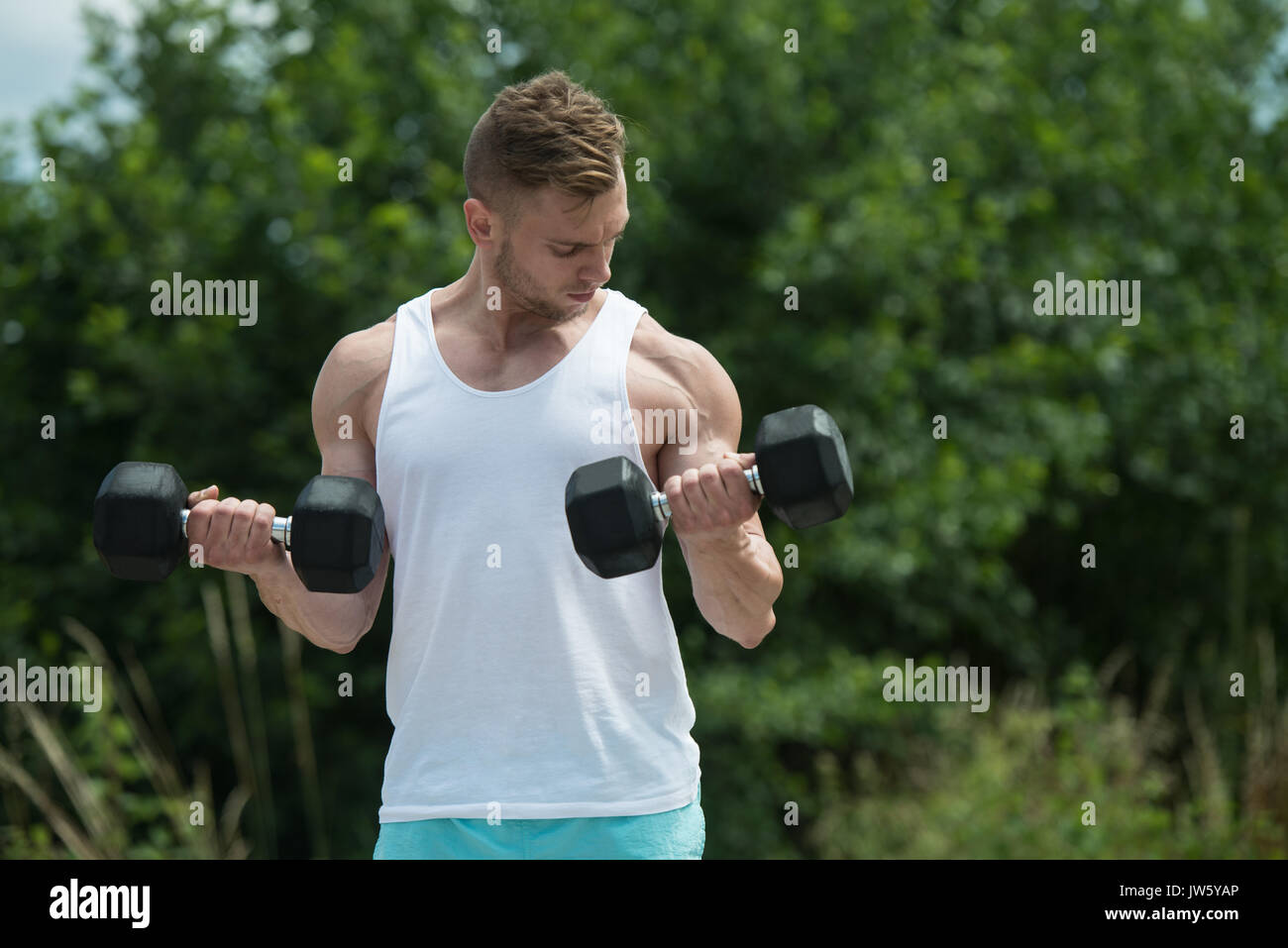 Athlete Working Out Biceps In Nature - Dumbbell Concentration Curls ...