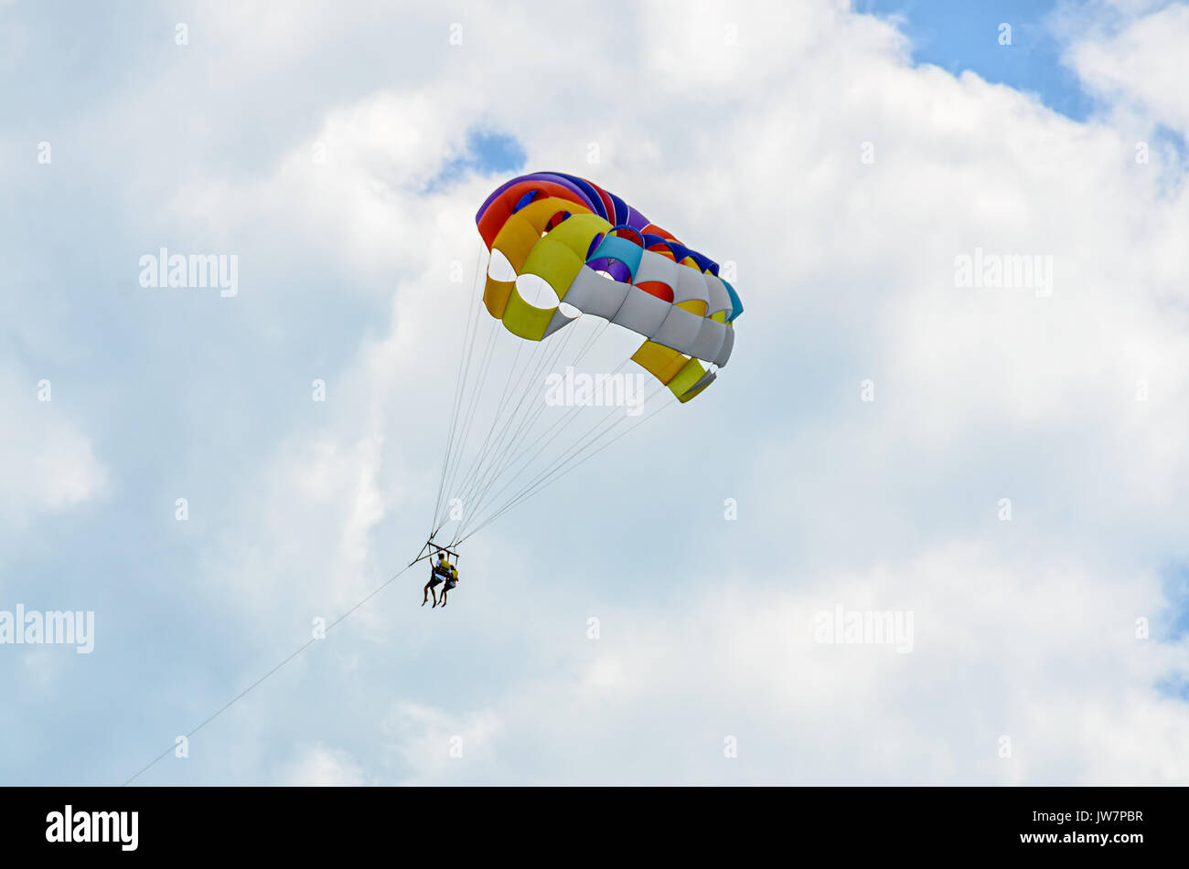 Colored parasail wing in the blue clouds sky, Parasailing also known as ...
