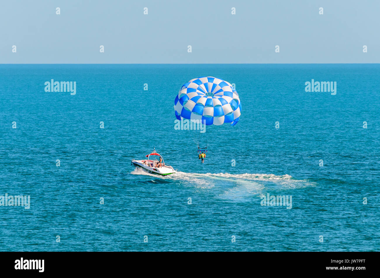 Blue parasail wing pulled by a boat in the sea water, Parasailing also ...