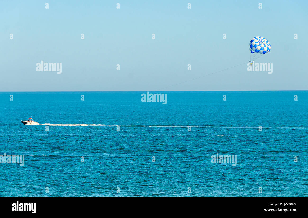 Blue parasail wing pulled by a boat in the sea water, Parasailing also ...