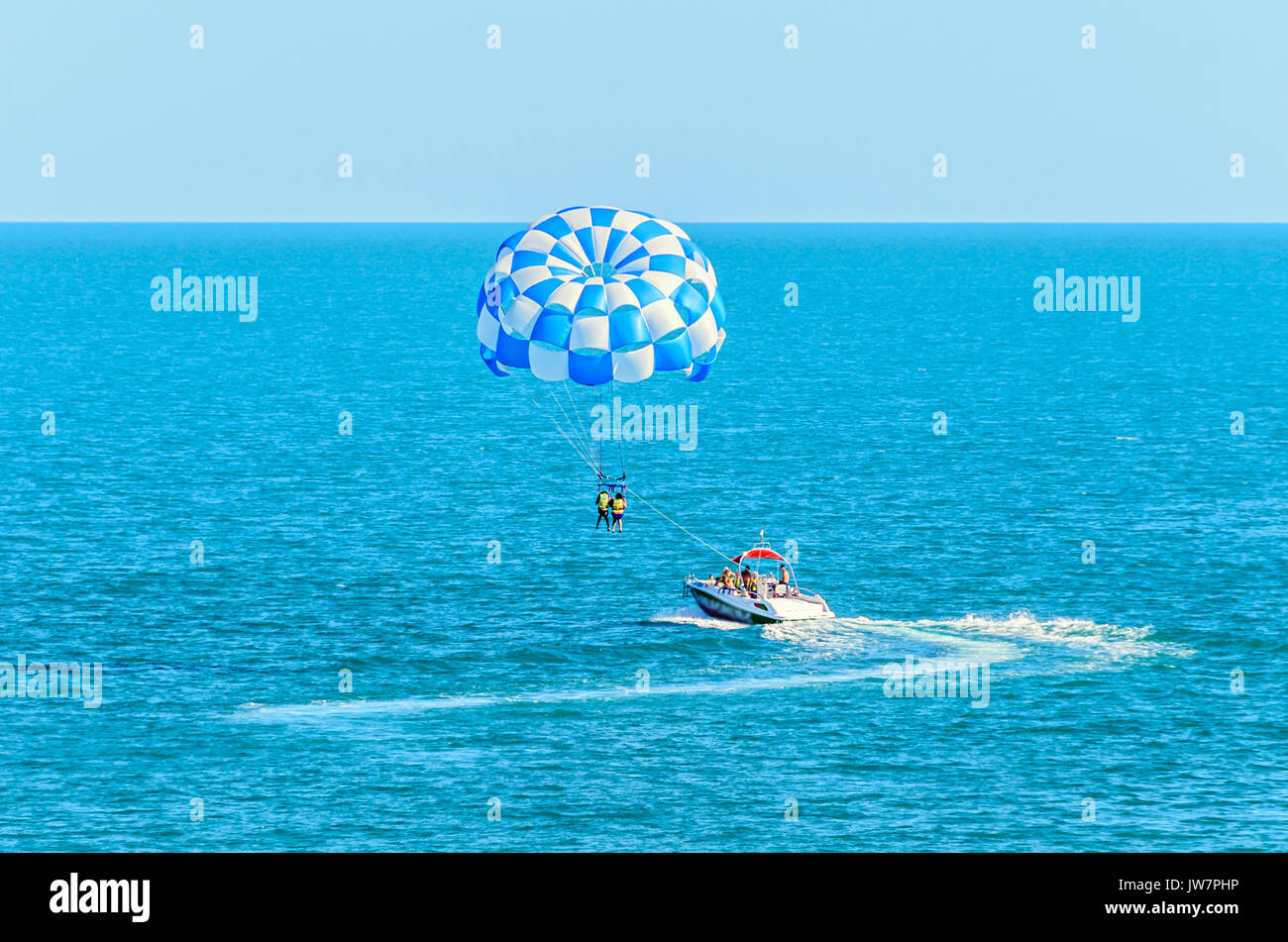 Blue parasail wing pulled by a boat in the sea water, Parasailing also ...