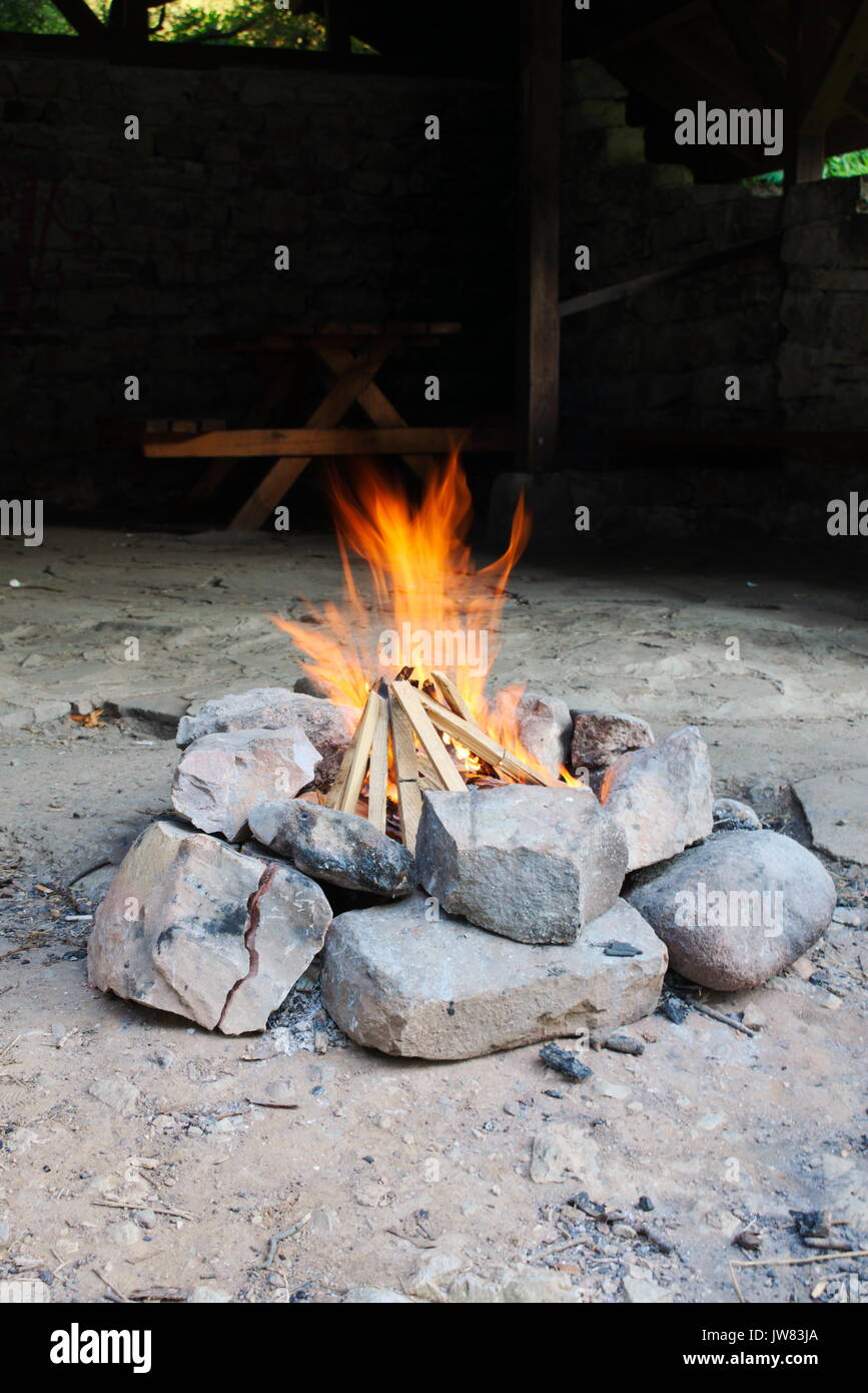 Campfire with a cabin bench in background Stock Photo - Alamy