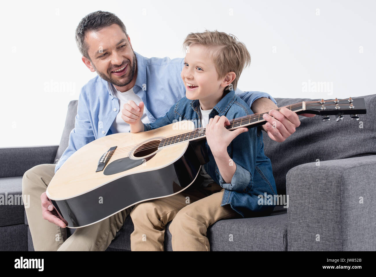 smiling father teaching his excited son to sing and play on guitar ...