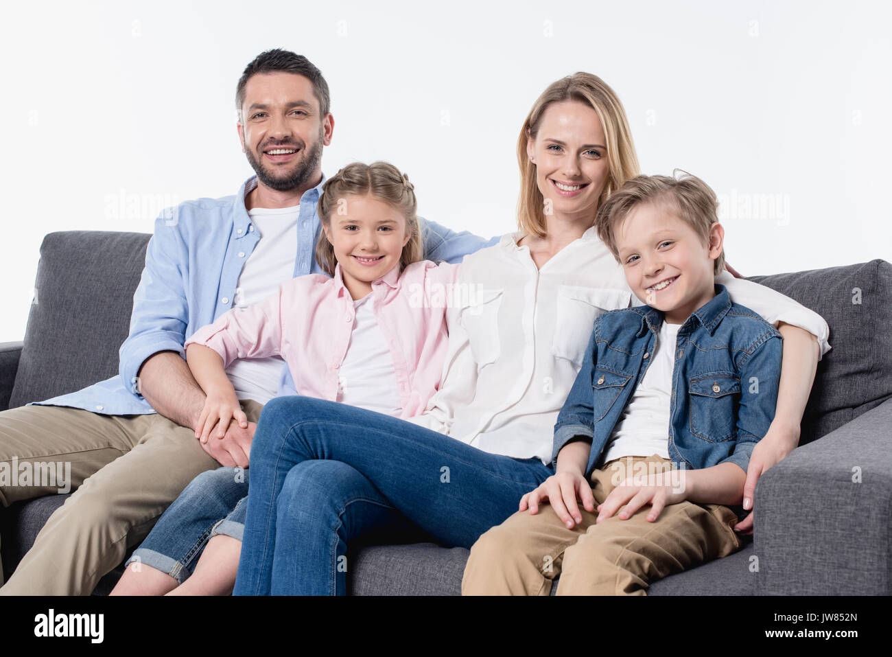 Happy family with two children sitting together on couch and smiling at ...