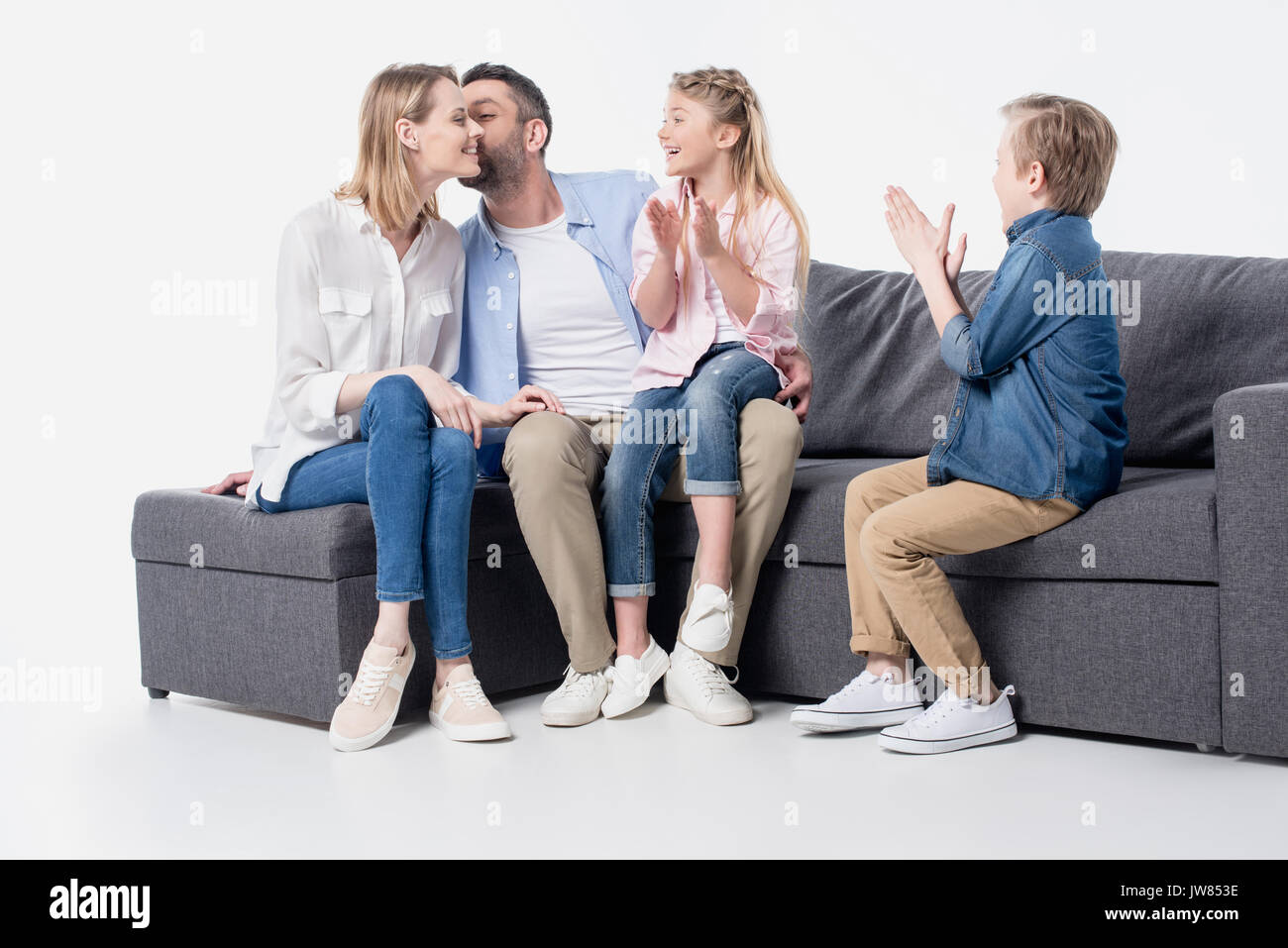 Cute happy children applauding to smiling parents sitting on sofa and ...