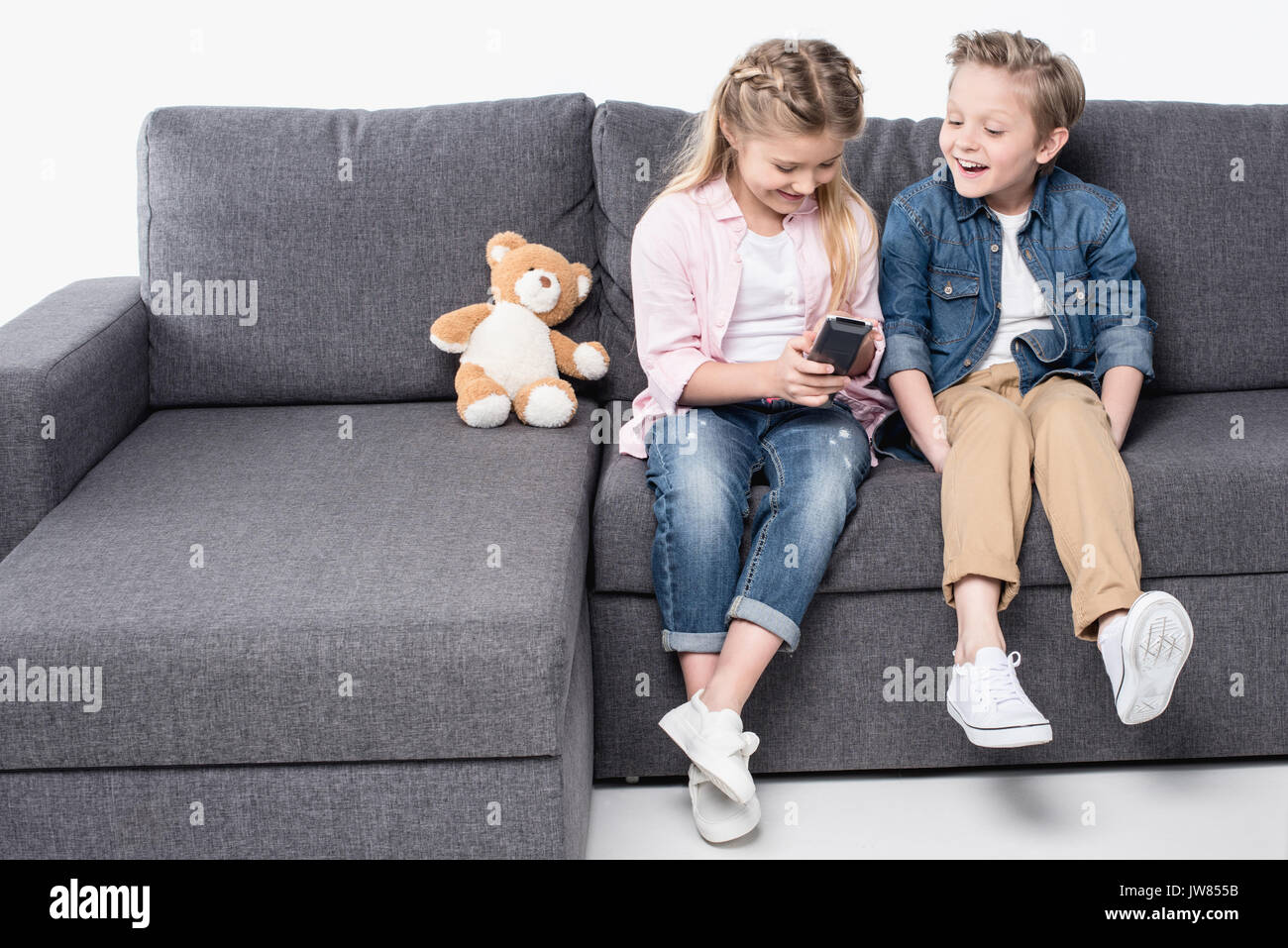happy brother and sister watching tv while spending time together ...