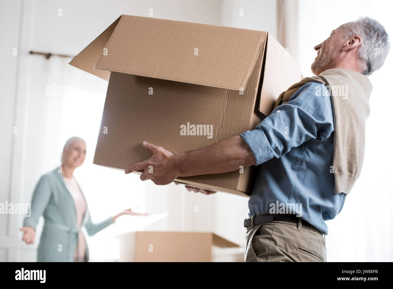 side view of man holding heavy cardboard box at new home Stock Photo ...