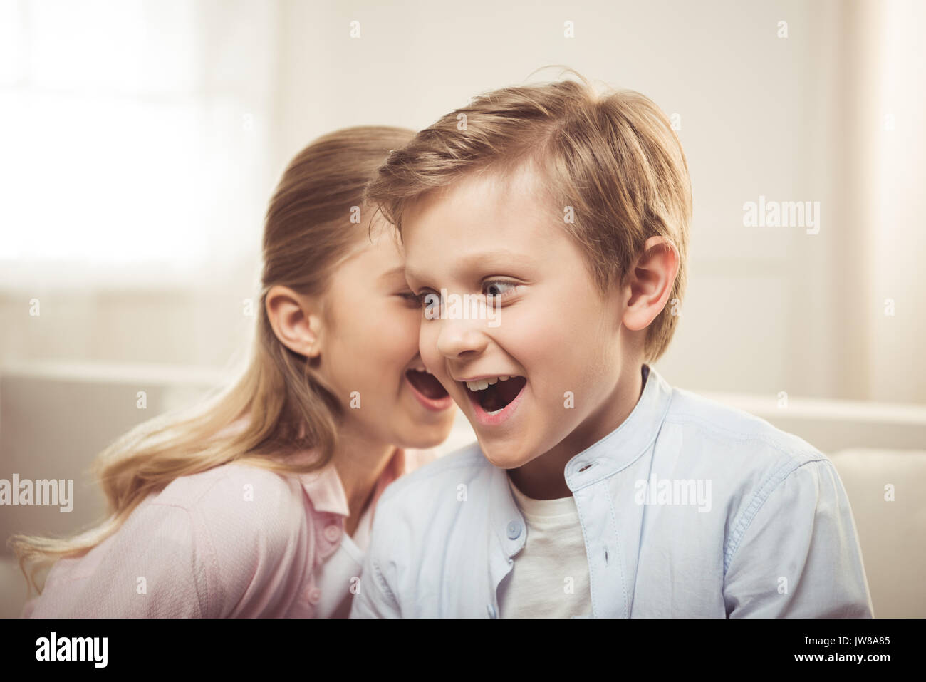 excited brother and sister talking and gossiping together while sitting ...