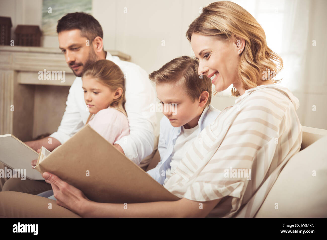 Happy family with two adorable children sitting together and reading ...