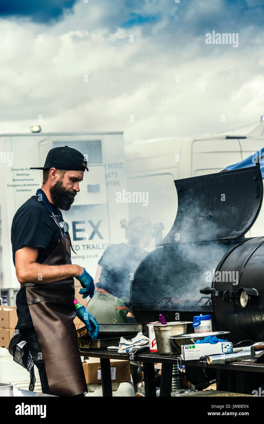 Chef cooking and smoking meat on a wood fired grill at an open air ...