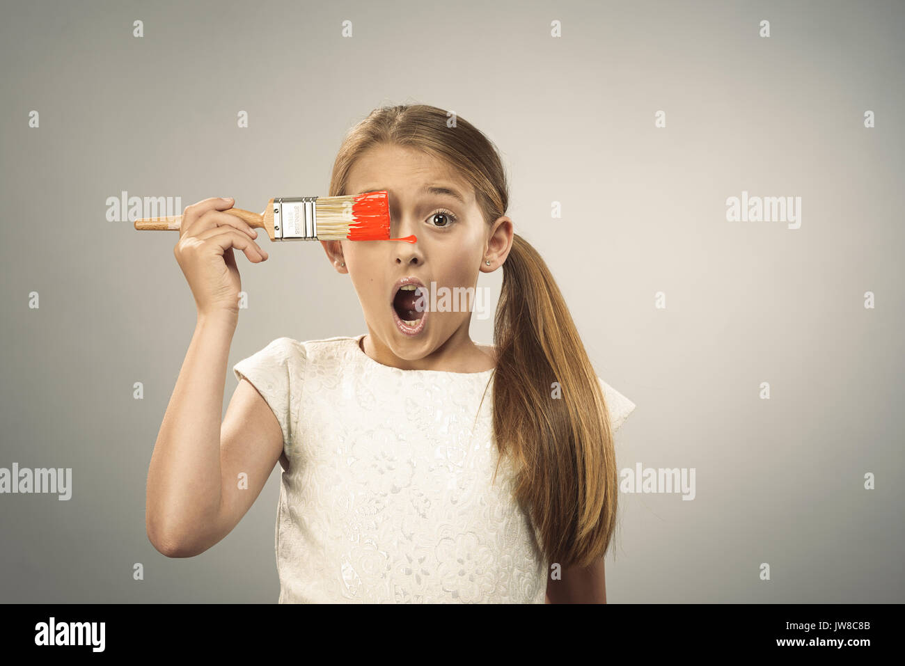 Young girl with paint brush, the drip of the paint running horizontally ...