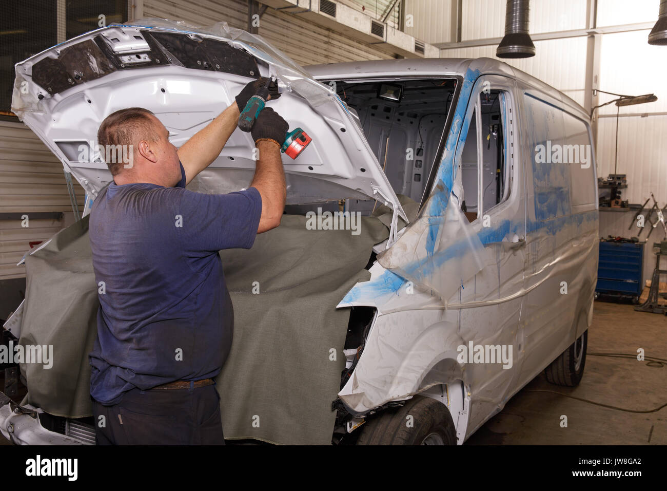 Mechanic repairing car with open hood Stock Photo - Alamy
