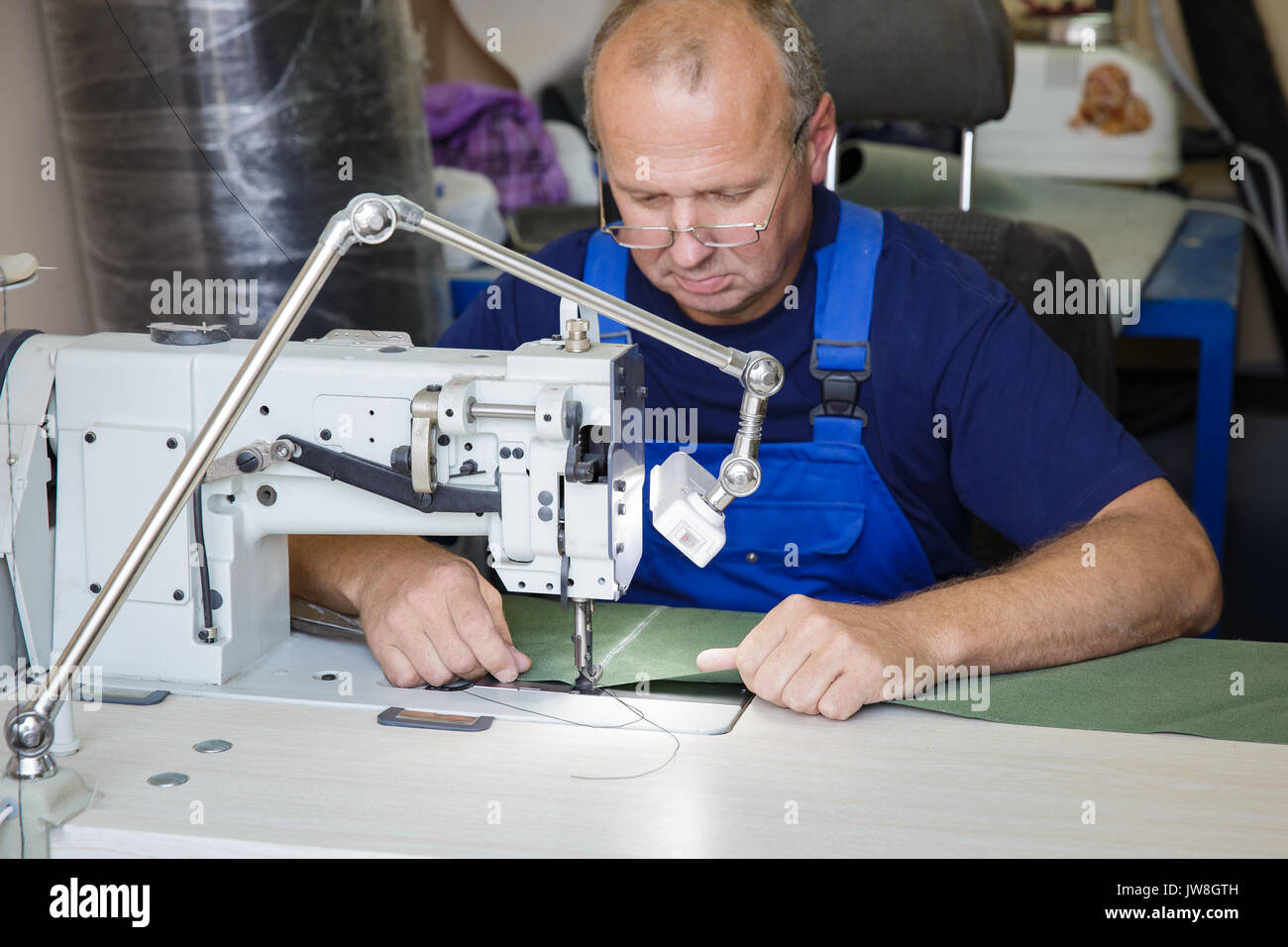 man seamsrtess sitting at the sewing machine Stock Photo - Alamy