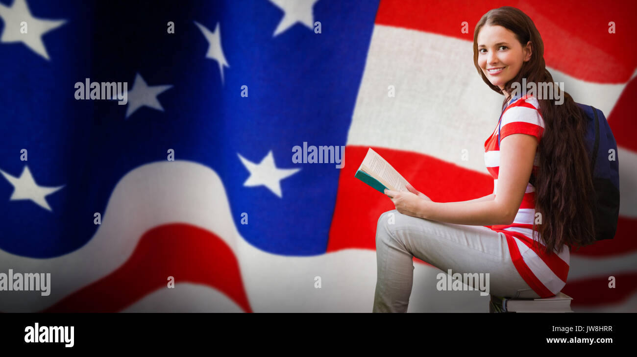 Student reading book in library against american flag with stripes and ...