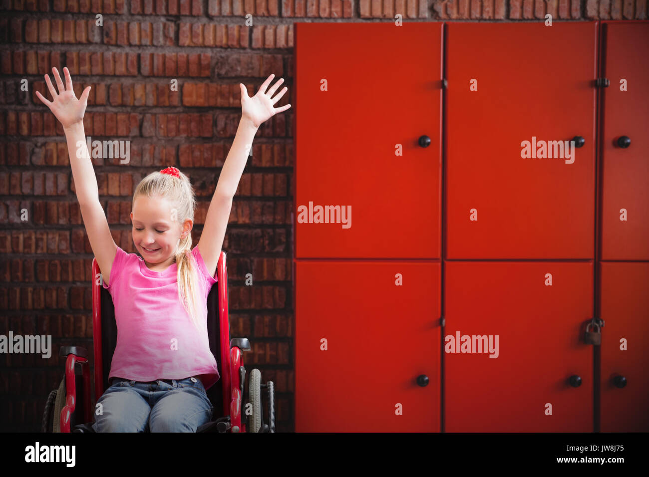 Cute disabled pupil smiling in hall against closed orange lockers ...