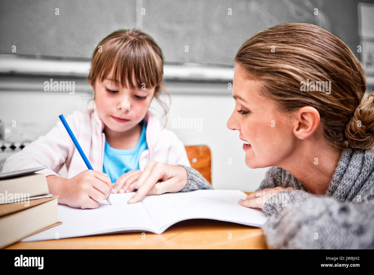 Schoolgirl writing with her smiling teacher in classroom Stock Photo ...