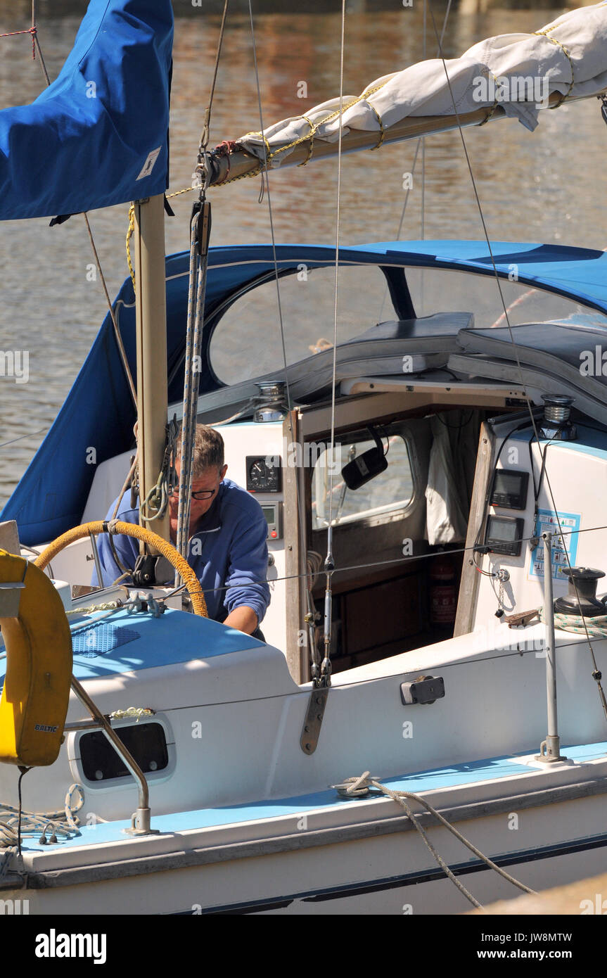 a man on a sailing boat yacht fixing or mending boat Stock Photo - Alamy