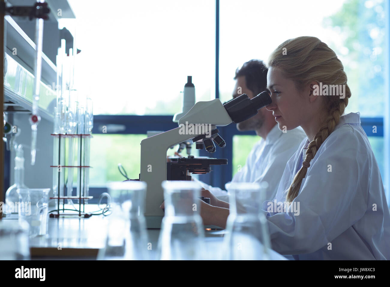 University students doing experiment on microscope in laboratory at ...