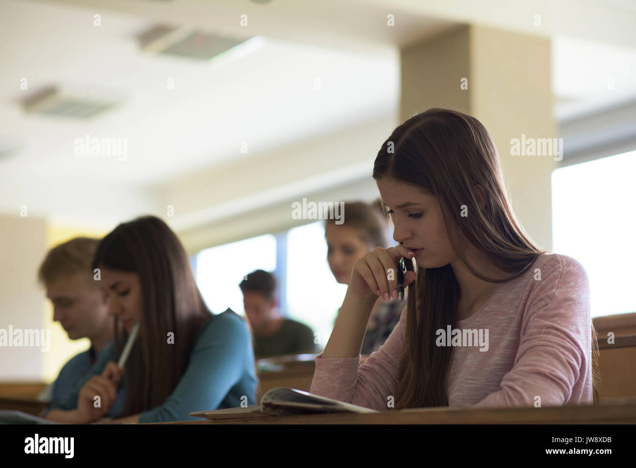 Low angle view of young college students at desk while sitting ...