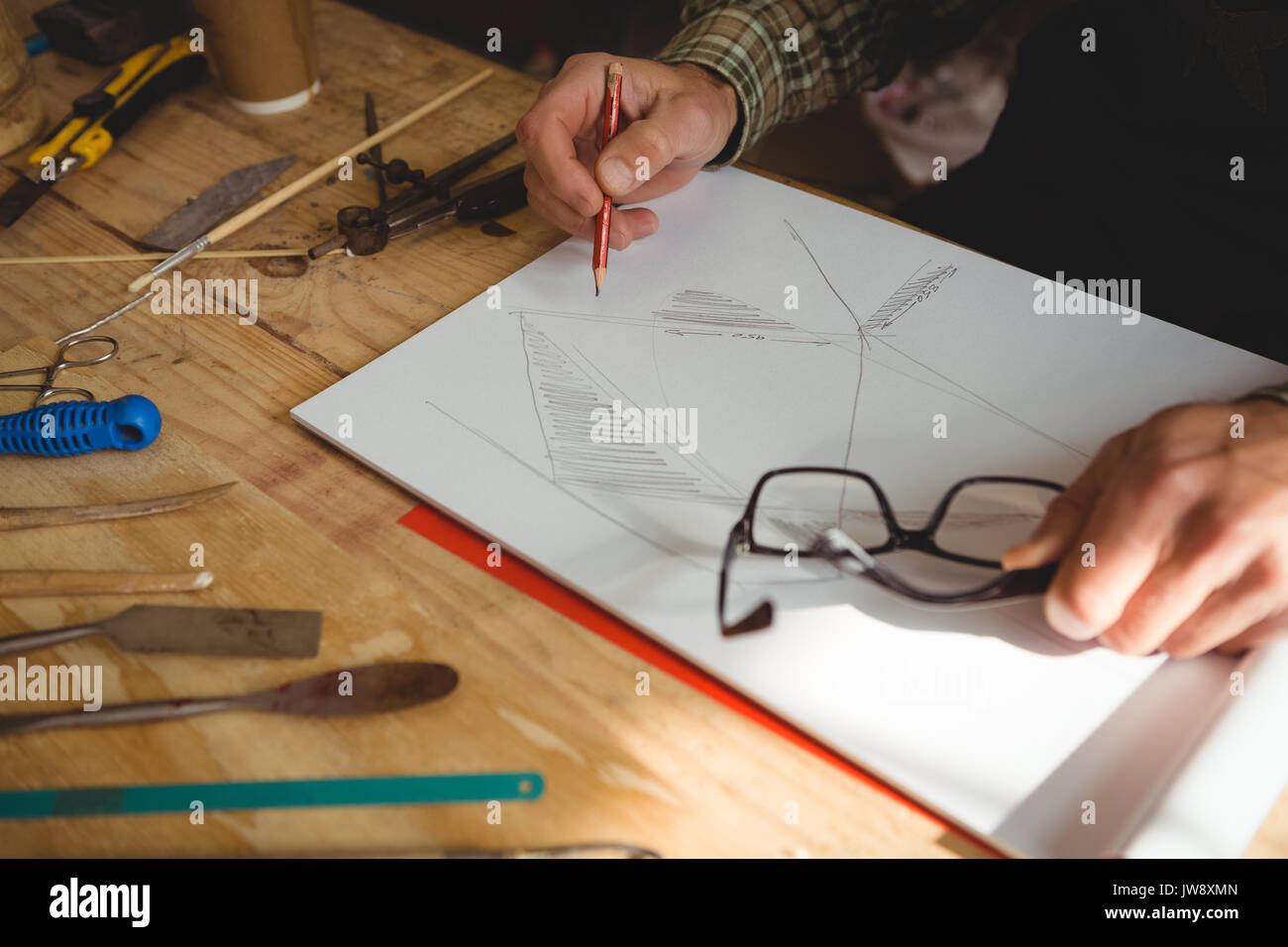 Mid-section of craftsman drawing sculpture design in workshop Stock ...