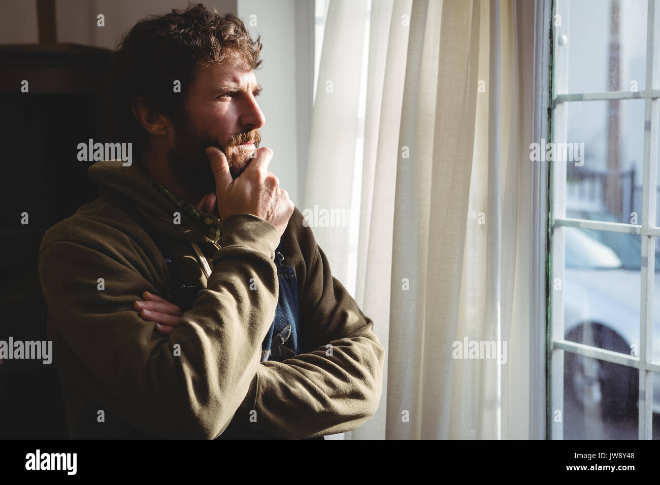 Craftsman looking through window in workshop Stock Photo - Alamy