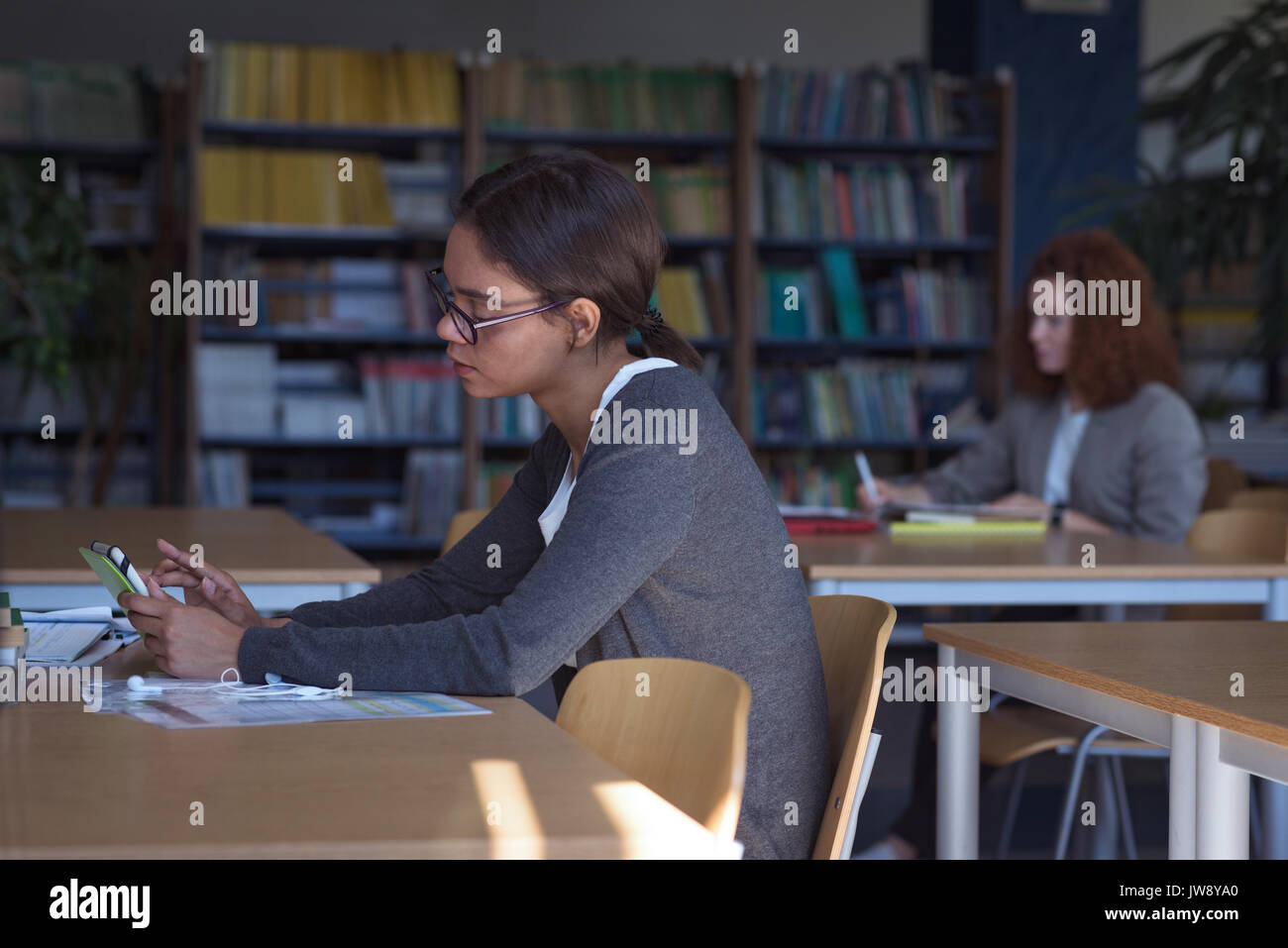 Female teenage students studying at desk in classroom Stock Photo - Alamy