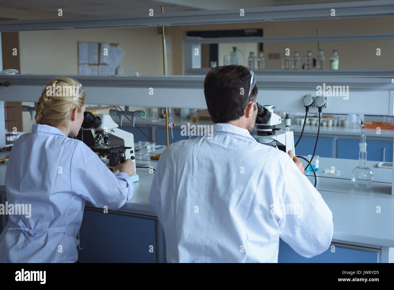 University students doing experiment on microscope in laboratory at ...