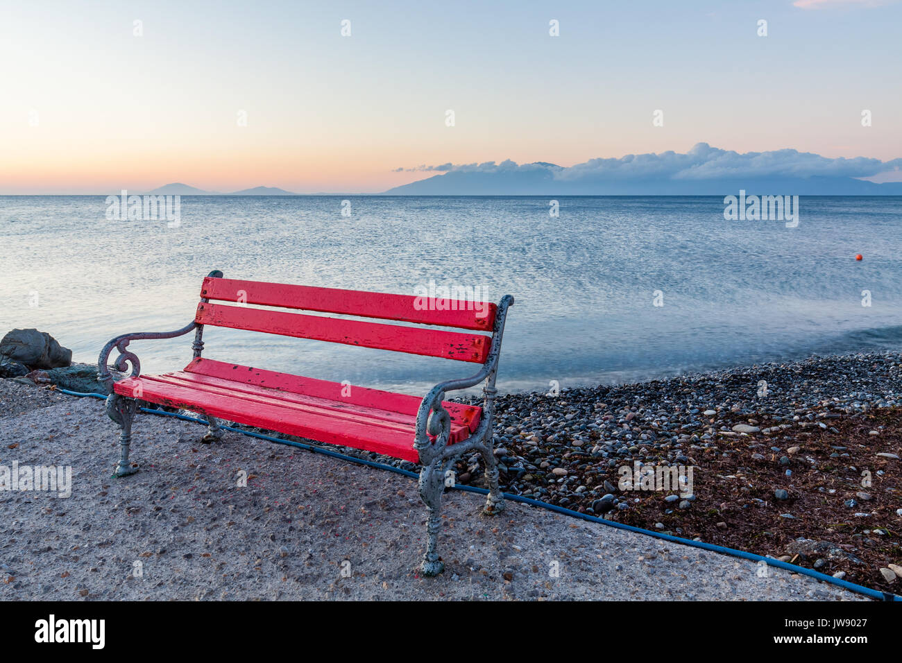 Empty red bench at seashore during sunrise Stock Photo - Alamy