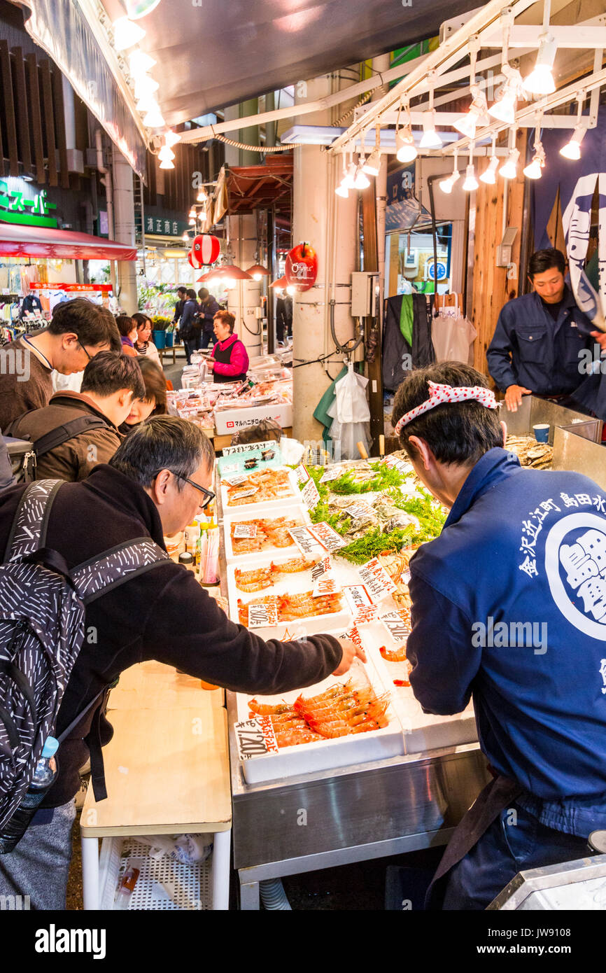View along Seafood and fish stall with man serving customer, background ...