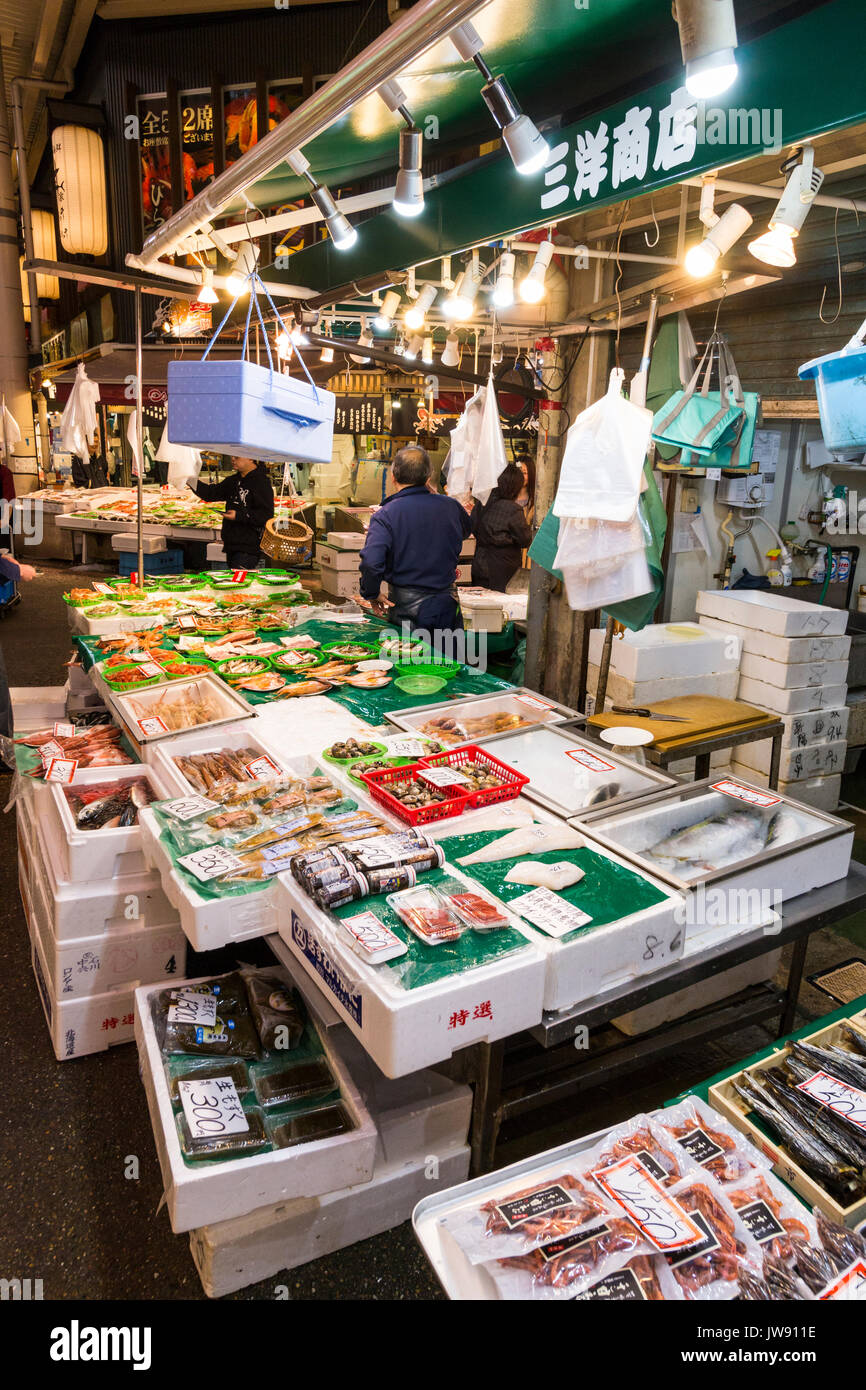 View along fresh seafood stall with various types of fish in containers ...