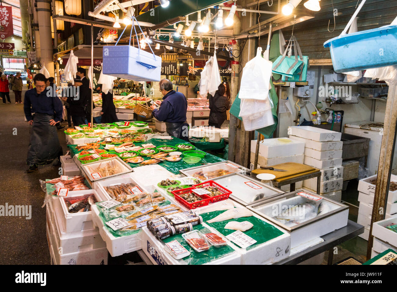 View along fresh seafood stall with various types of fish in containers ...
