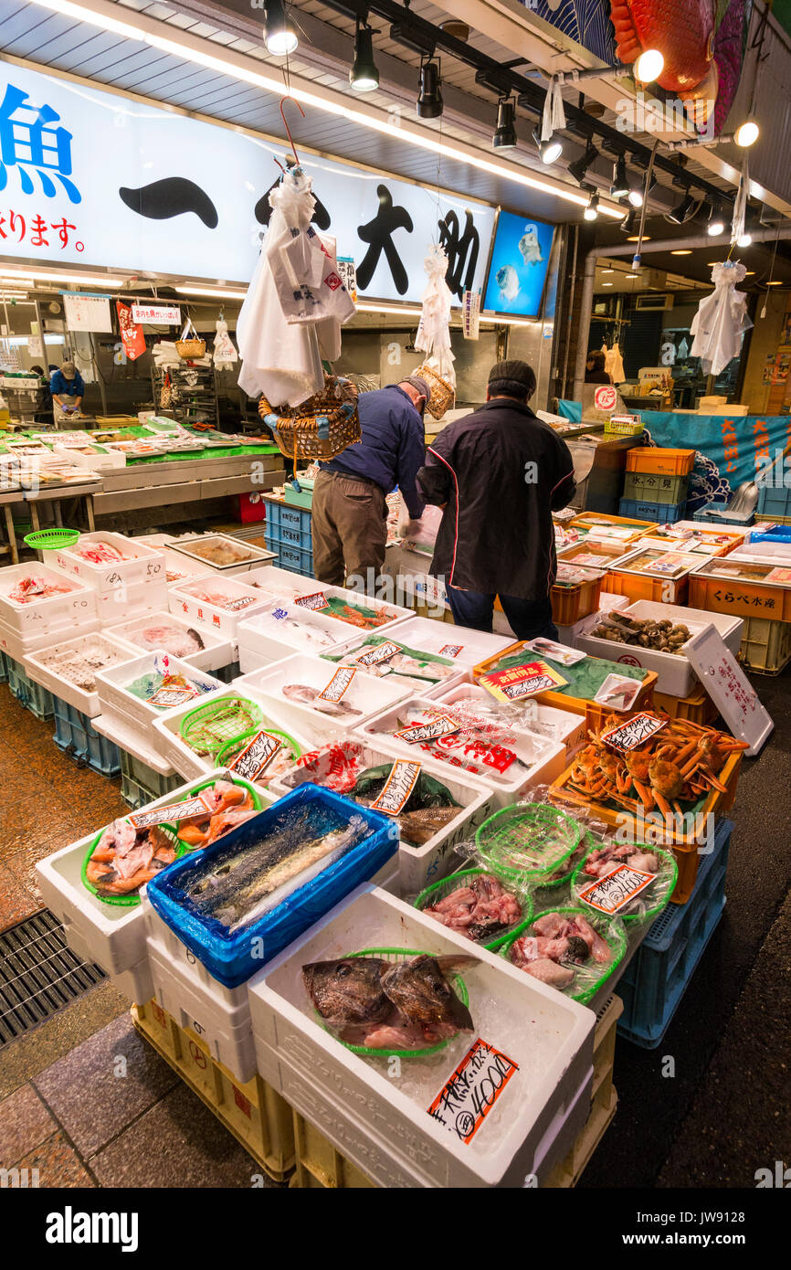 Fresh seafood stall with various types of fish in plastic containers on ...