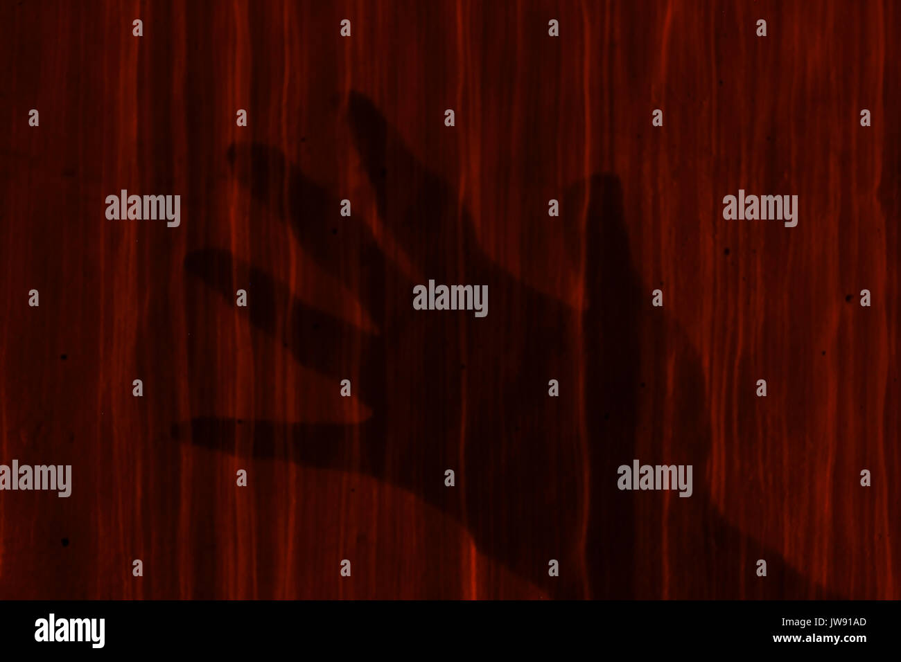 A shadow from a hand on a red wall. Light from a street lamp on the ...