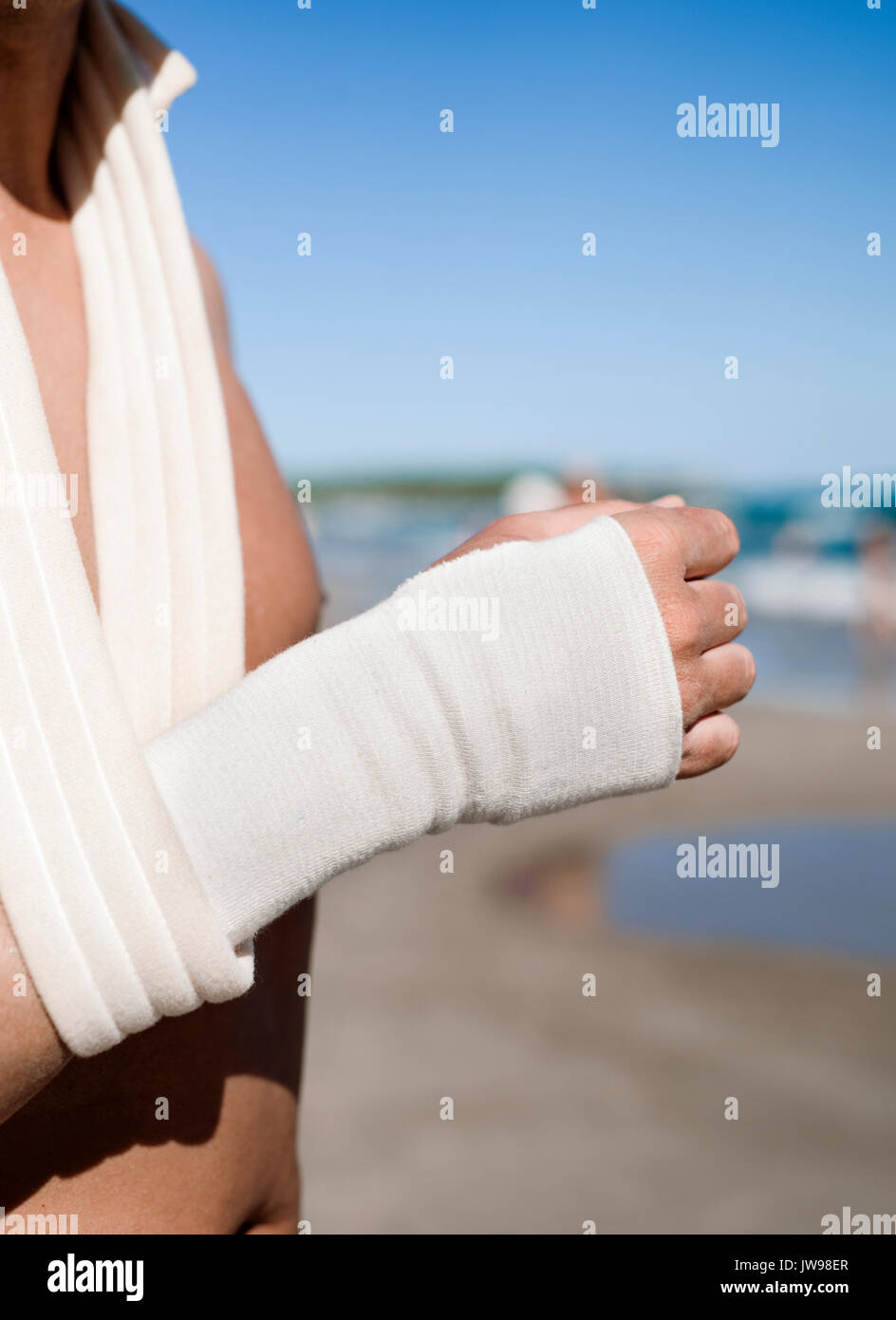 closeup of a young caucasian man on the beach with a sling and a ...