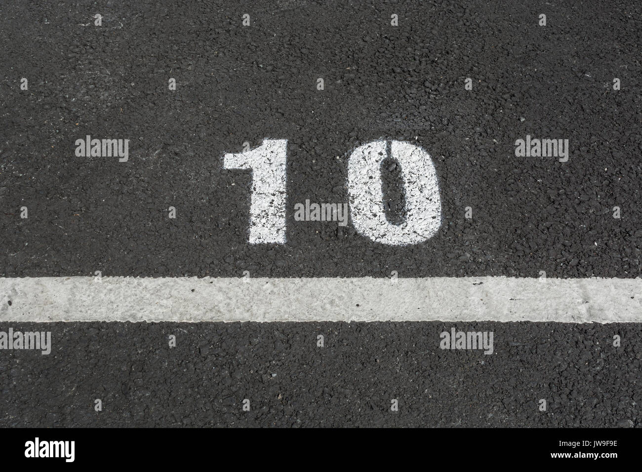 Painted number 10 on tarmac car parking space / parking lot space. Even ...