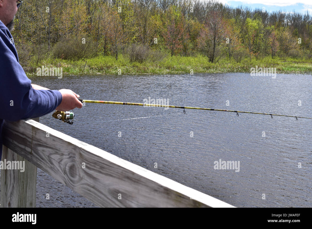Man fishing off a bridge Stock Photo - Alamy