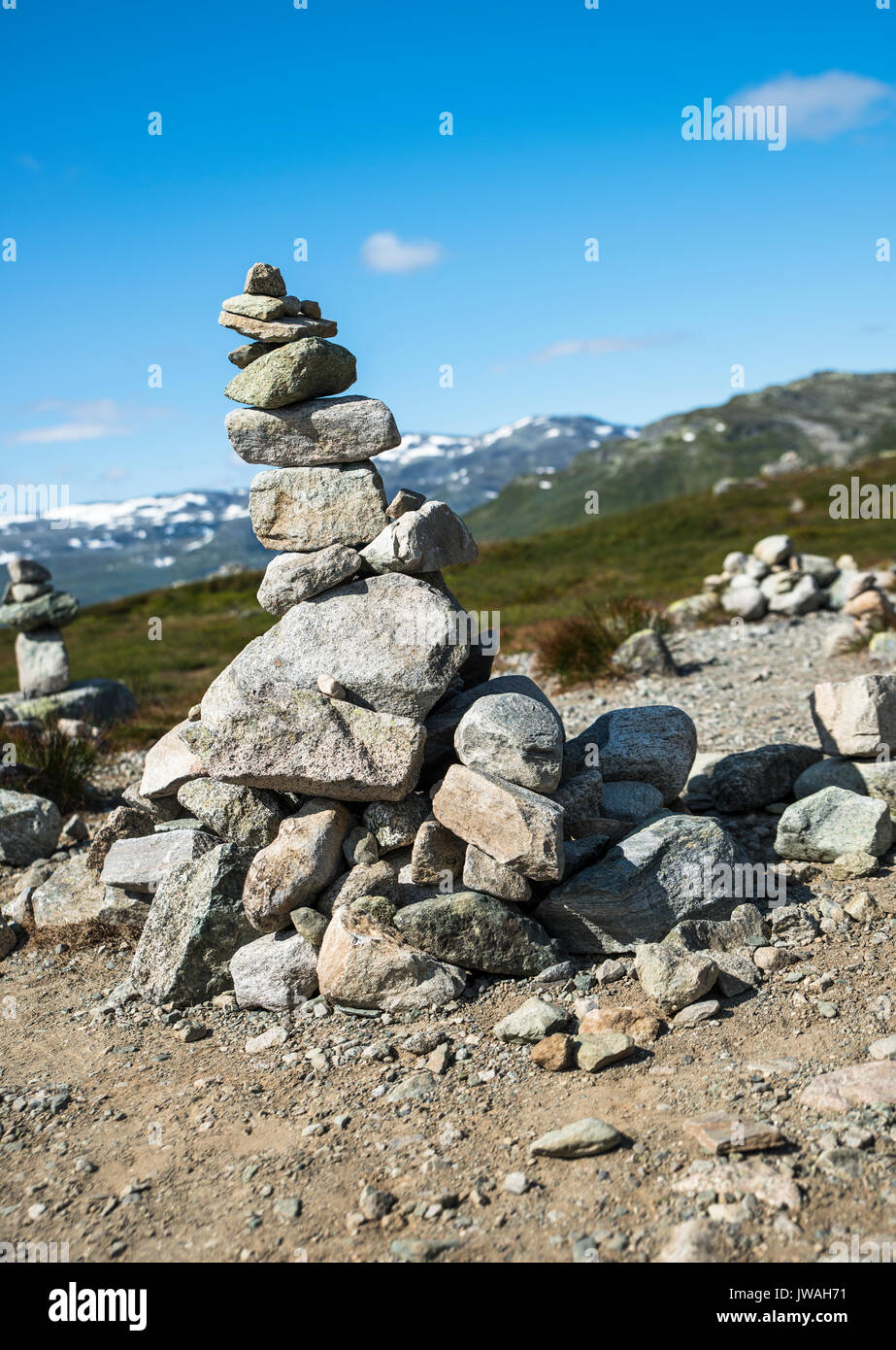balanced stack of stones at Eidfjorden, Norway with snow and mountains ...