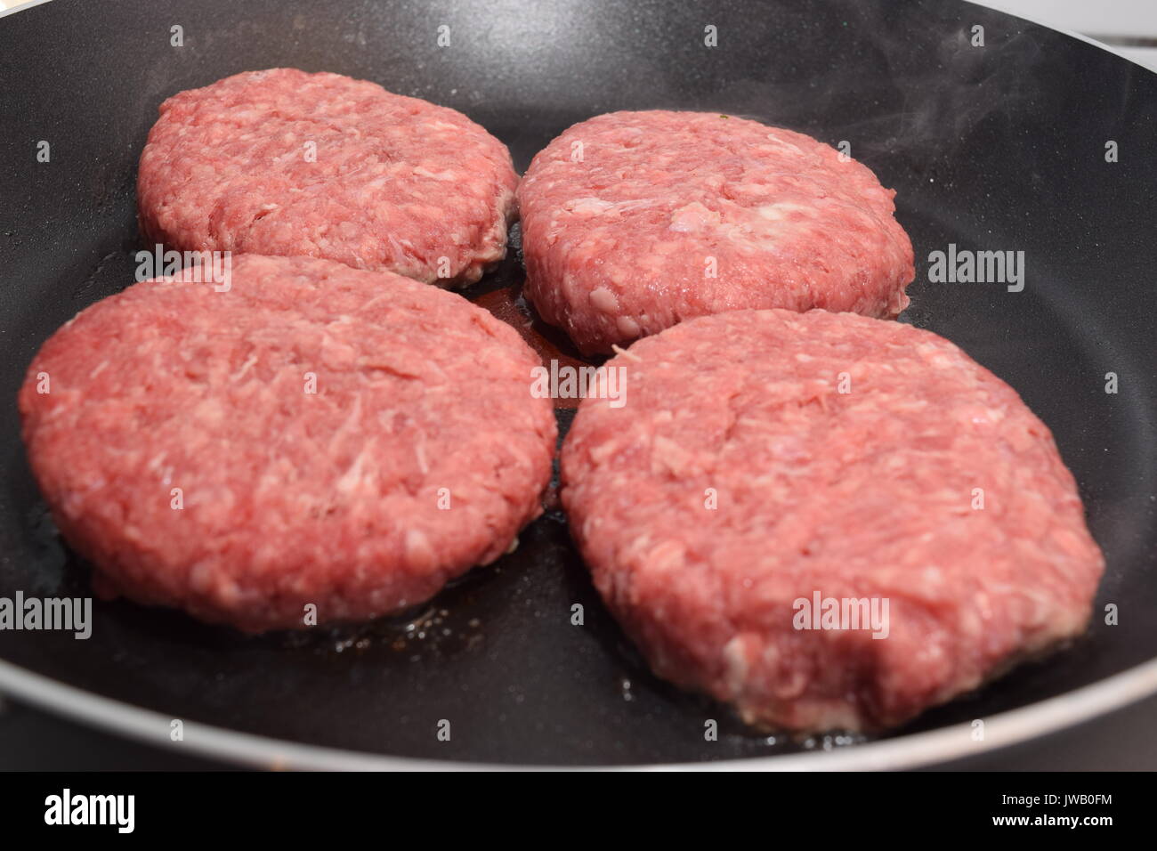 Uncooked beef burgers in a pan Stock Photo - Alamy