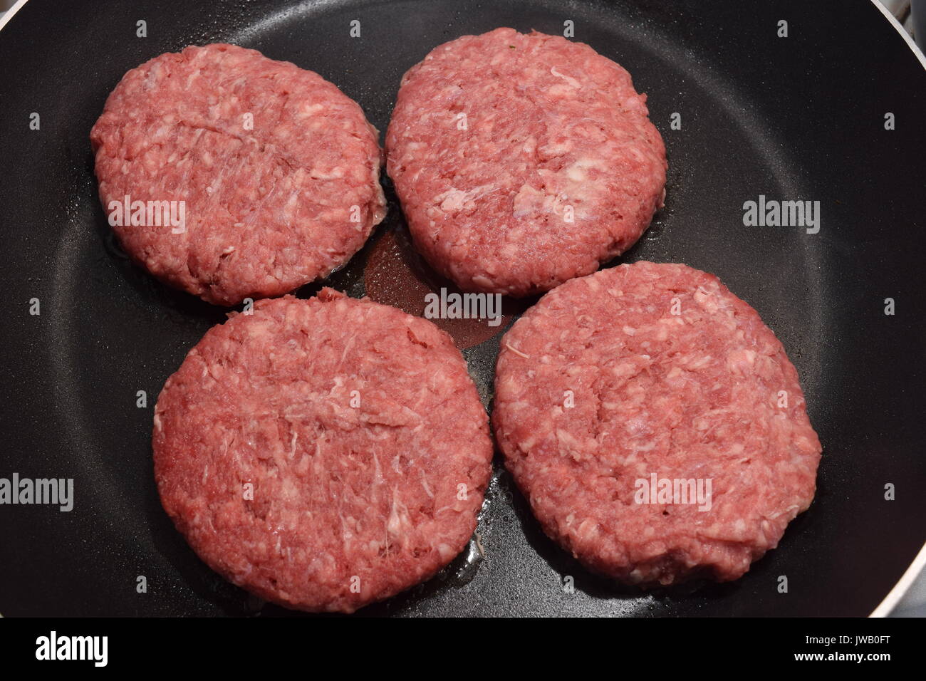Uncooked beef burgers in a pan Stock Photo - Alamy