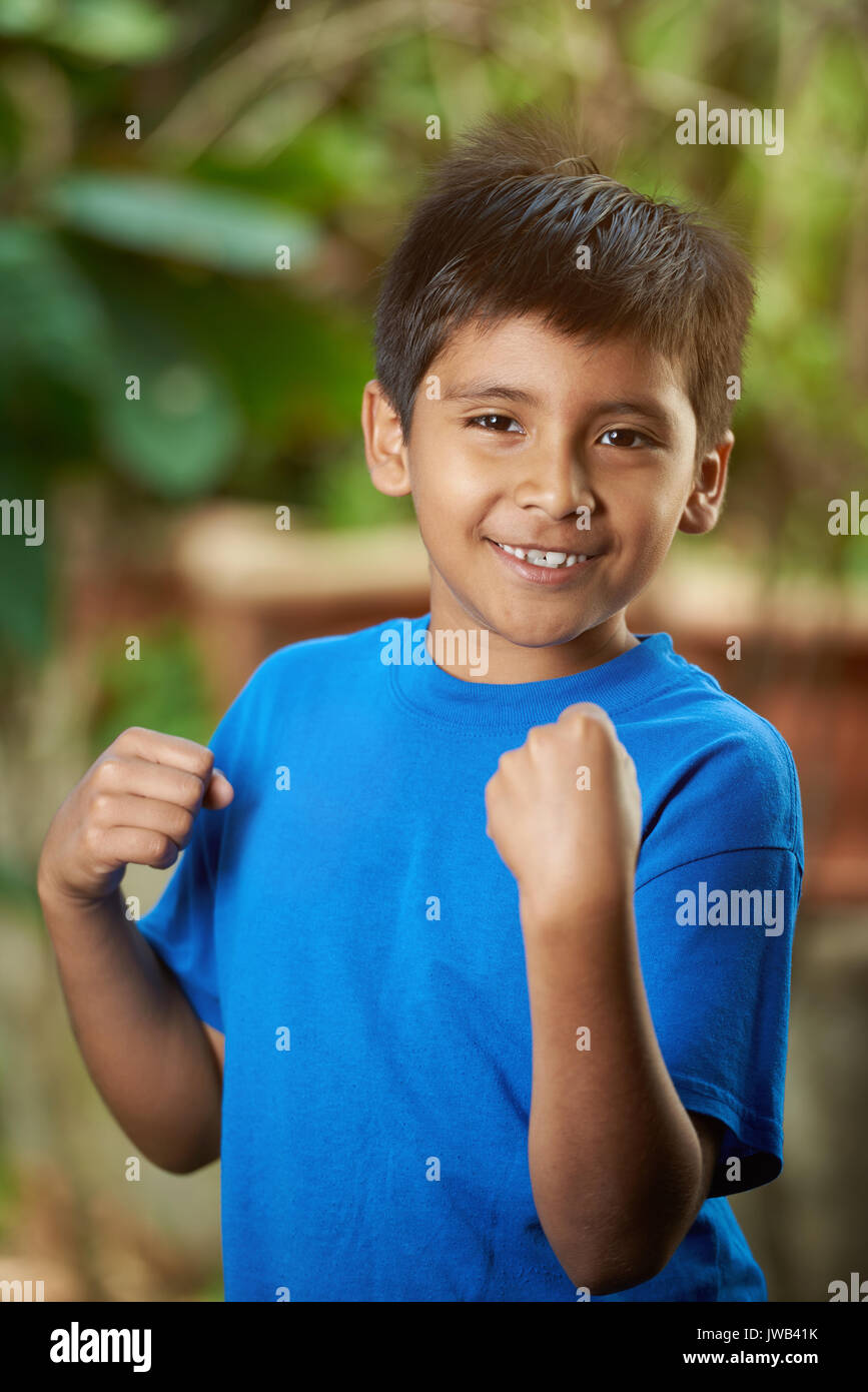 Funny small boy showing muscle on blurred green background Stock Photo ...