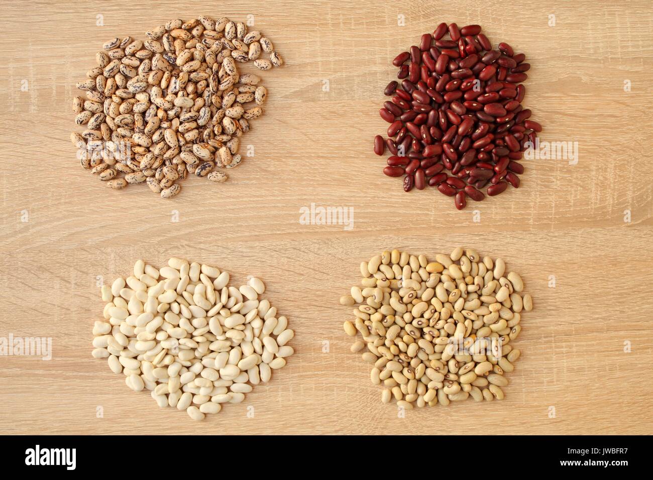 Four varieties of common beans on wooden table Stock Photo - Alamy