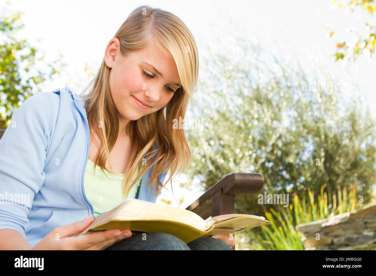 Young teen girl outside reading in the backyard Stock Photo - Alamy