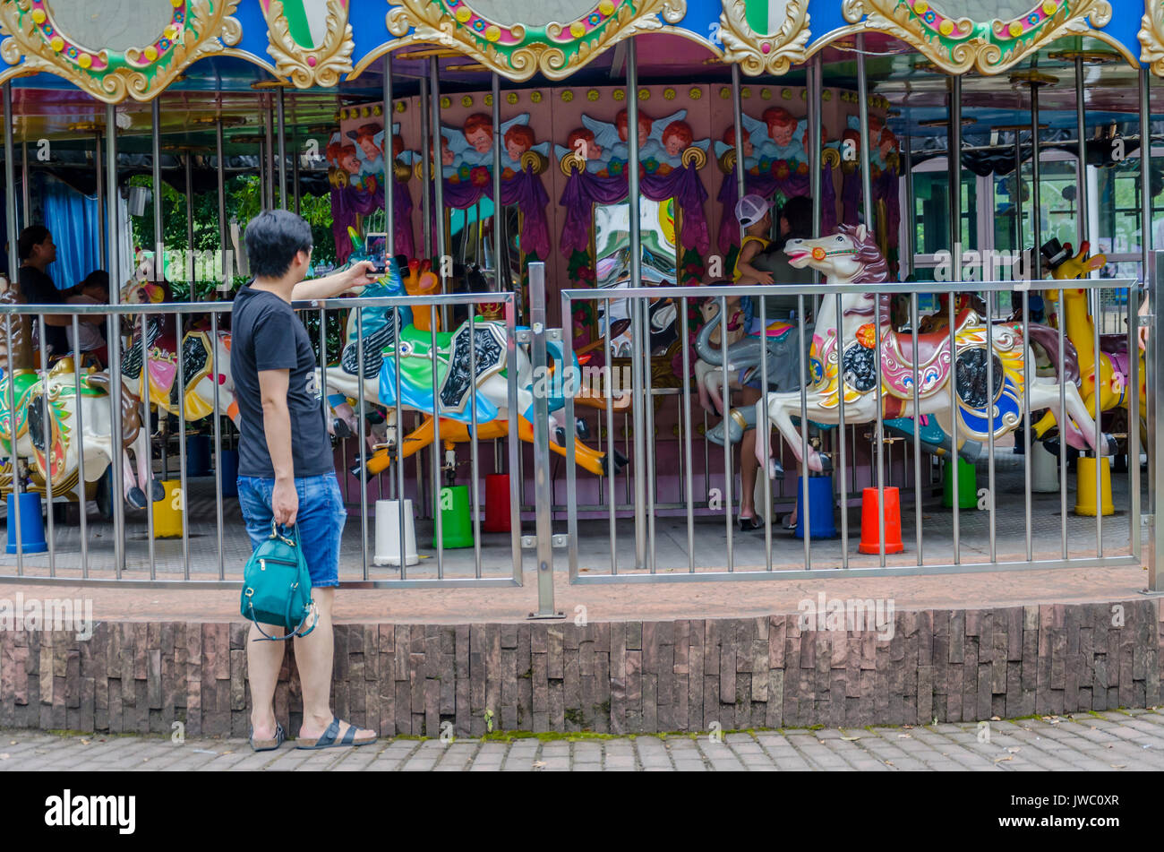 A father takes a picture of his family riding a merry-go-round in the ...