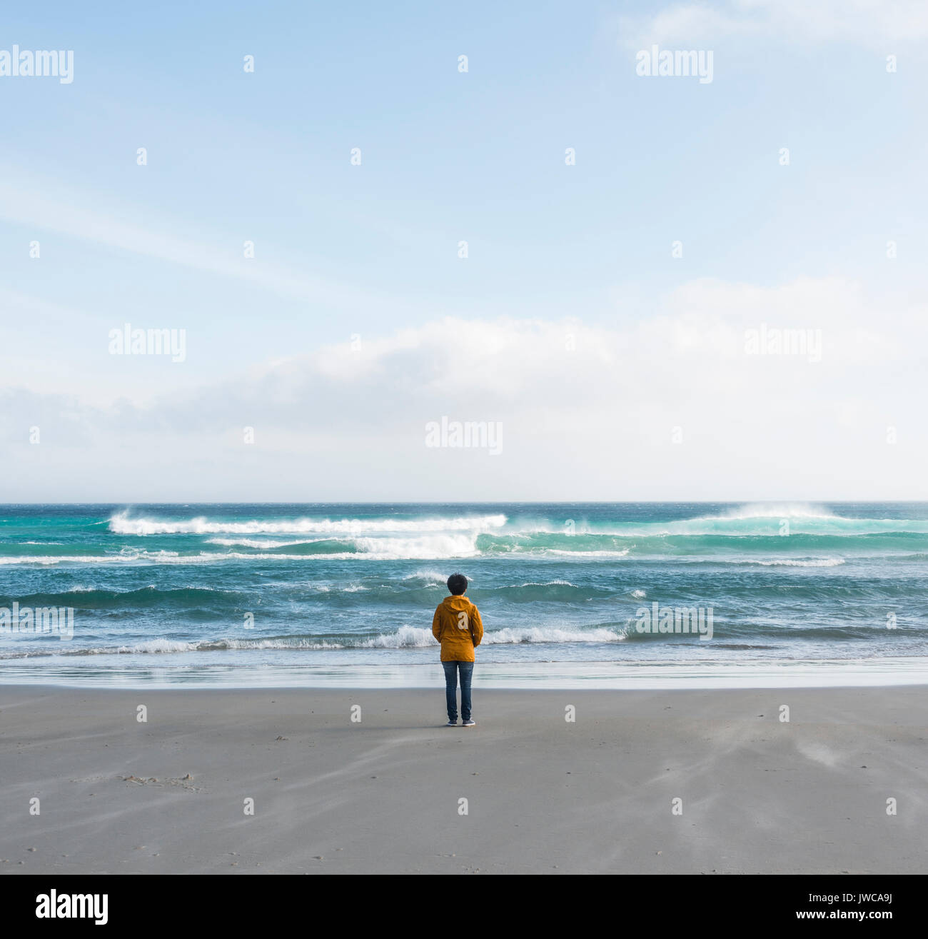 Lonely person standing by the sea, looking out into the distance ...