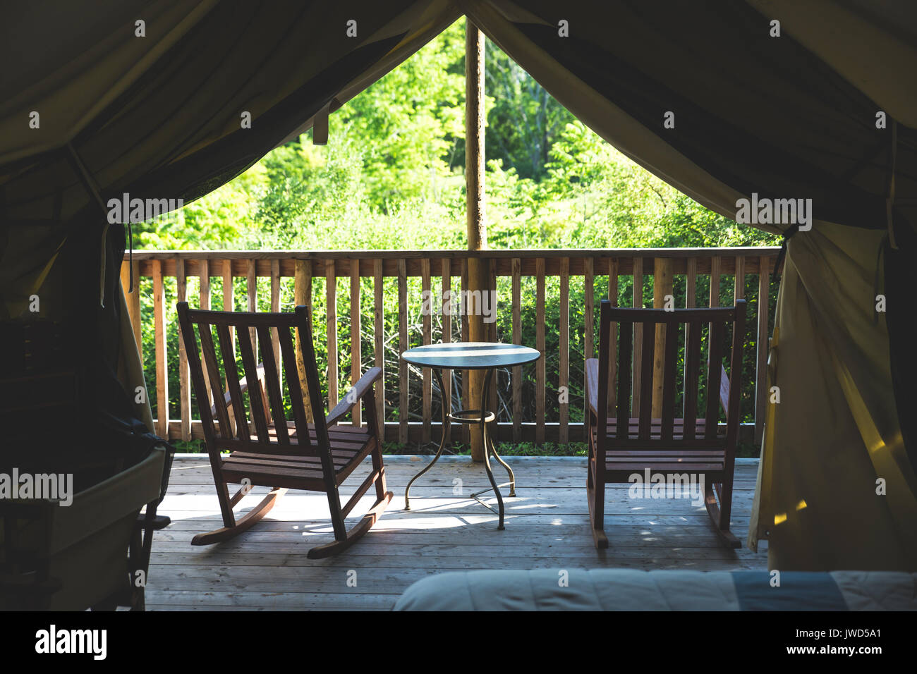 Interior of tent cabin in the woods with two chairs and table on deck ...