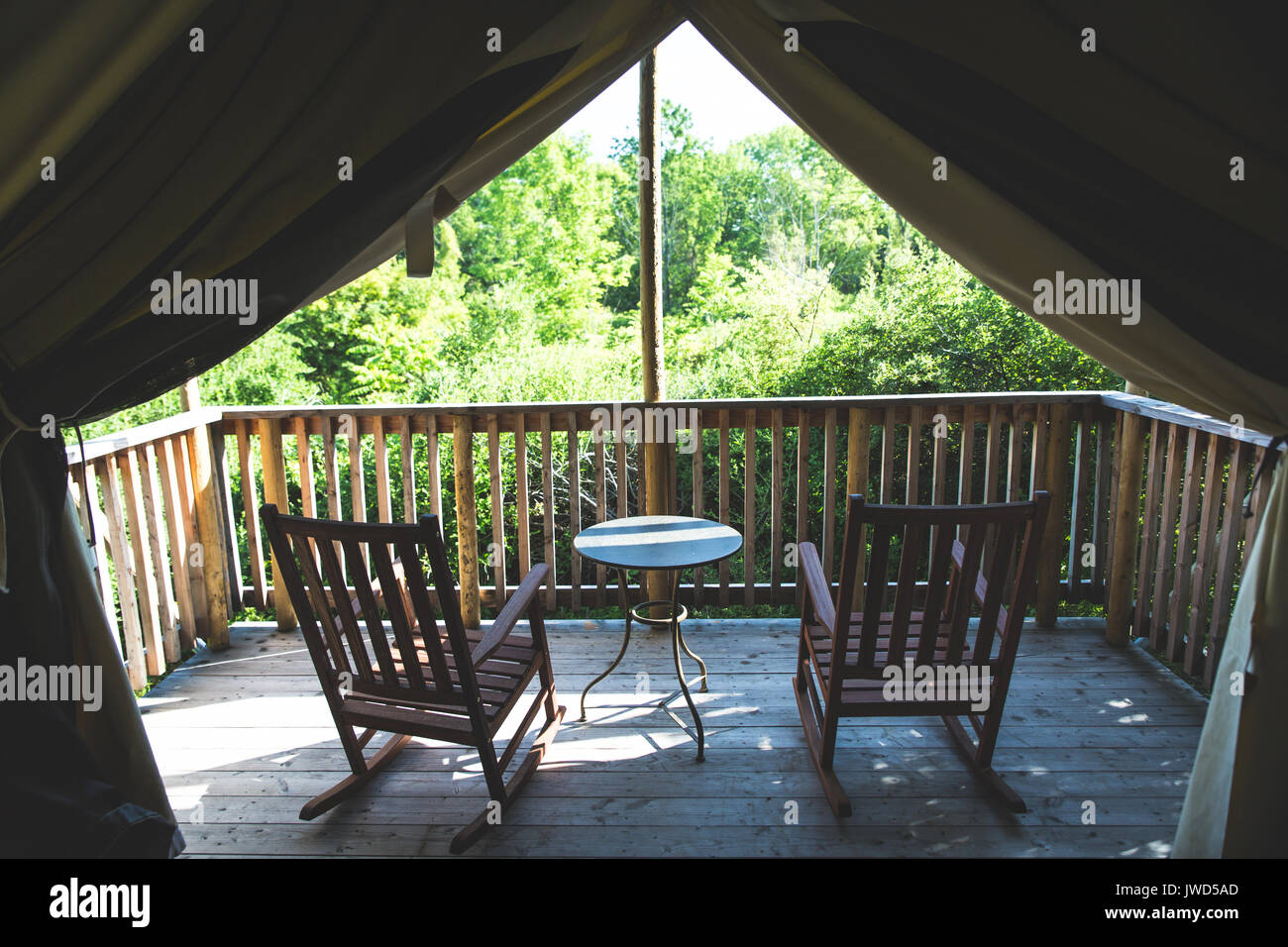 Interior of tent cabin in the woods with two chairs and table on deck ...