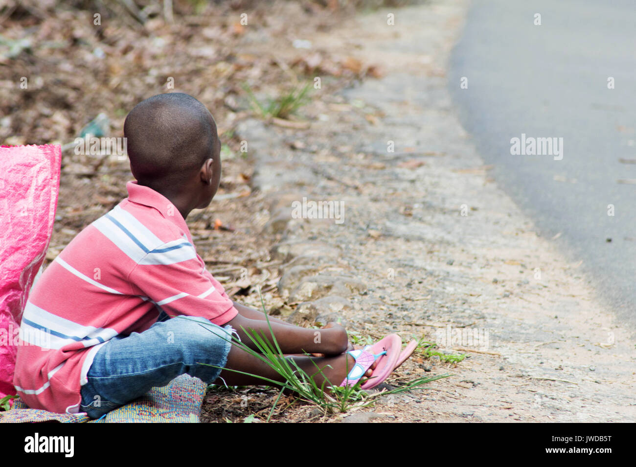 a child sitting on the ground and beside him a bag Stock Photo - Alamy